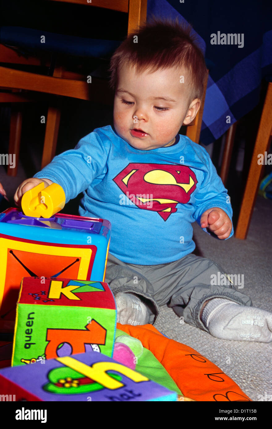 Baby Boy Sitting On Floor Playing With Toy Stock Photo - Alamy