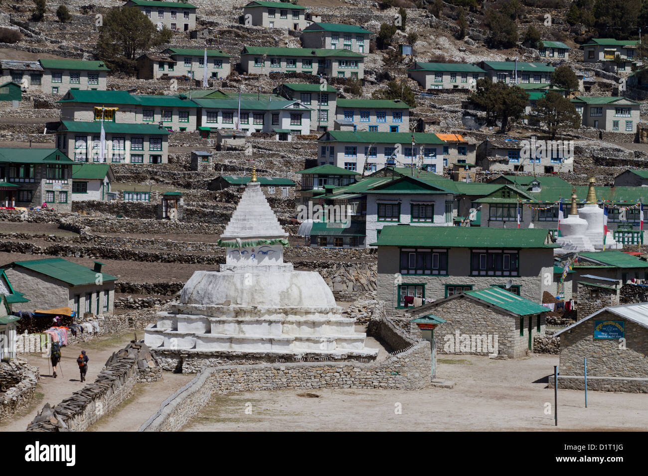 Trekkers walk past the White Gompa and Stupa in the Nepalese Village of ...