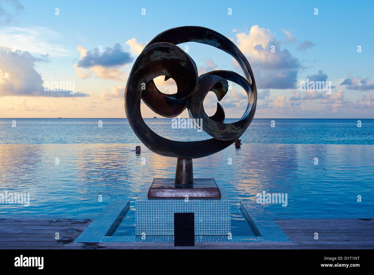 Couple swimming in an infinity pool with sculpture at sunset in the ...