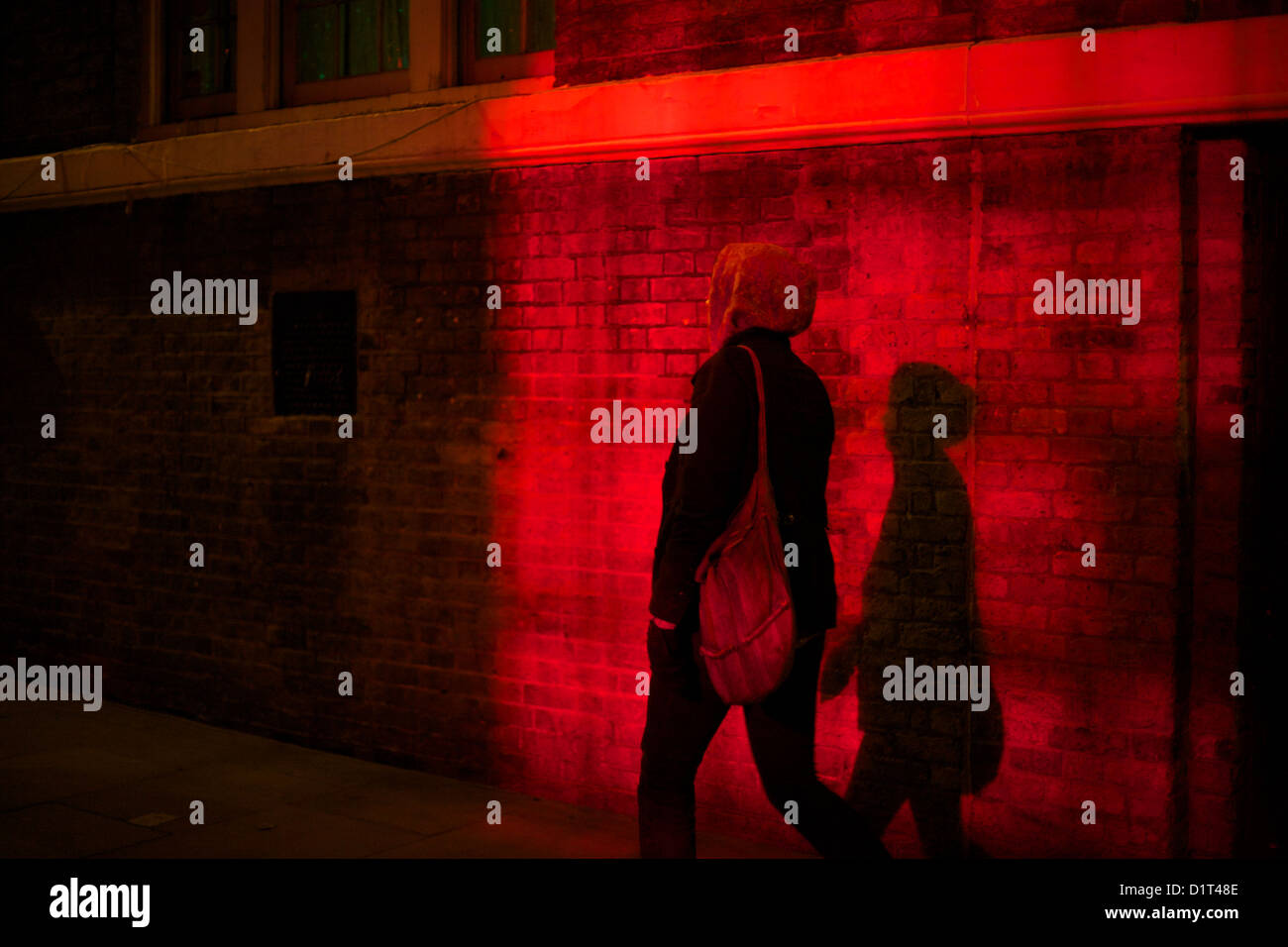 person walking down a street lit red Stock Photo - Alamy