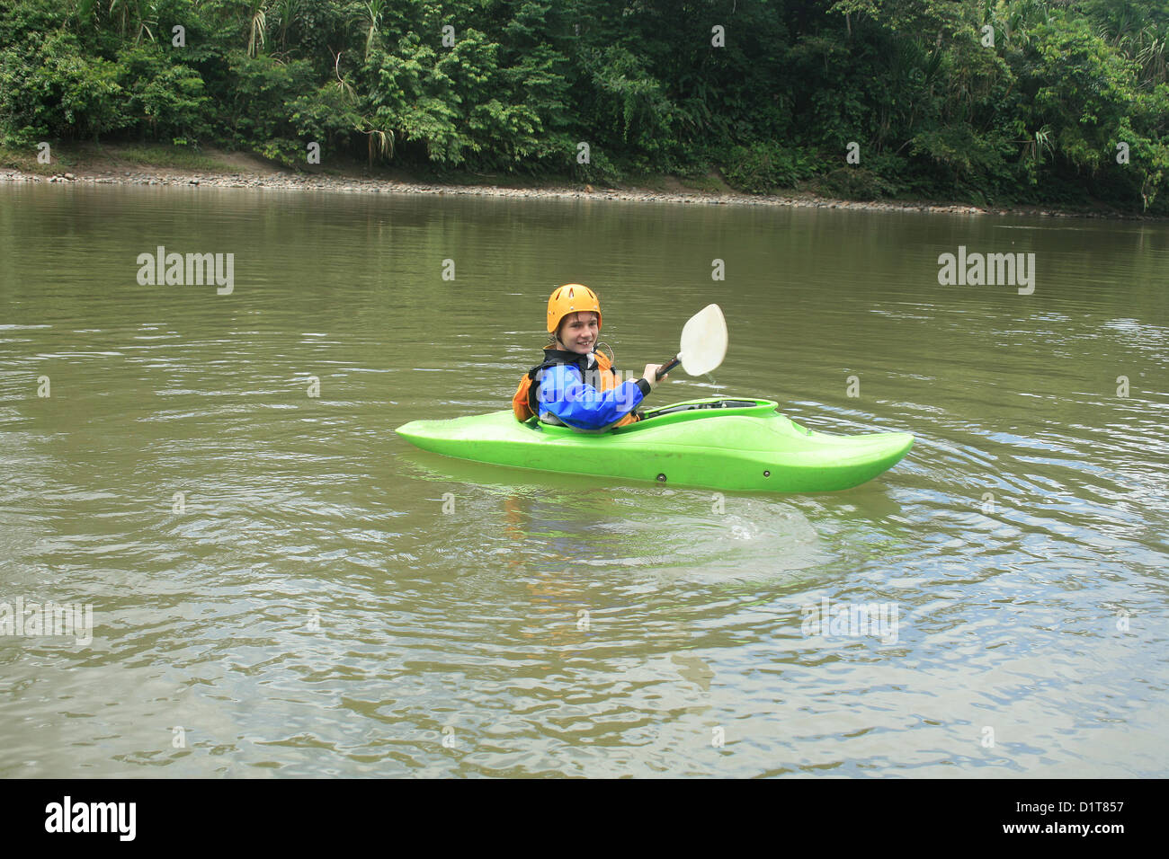 A male teenager paddling a kayak down the Napo River in the Ecuadorian ...