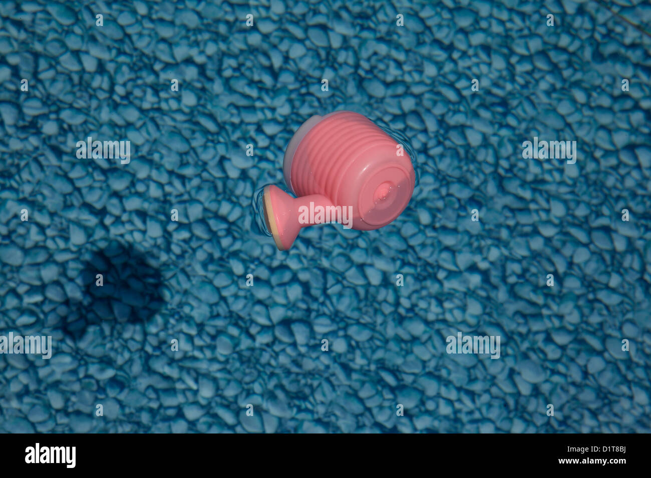 pink and white plastic watering can floating in swimming pool Stock ...