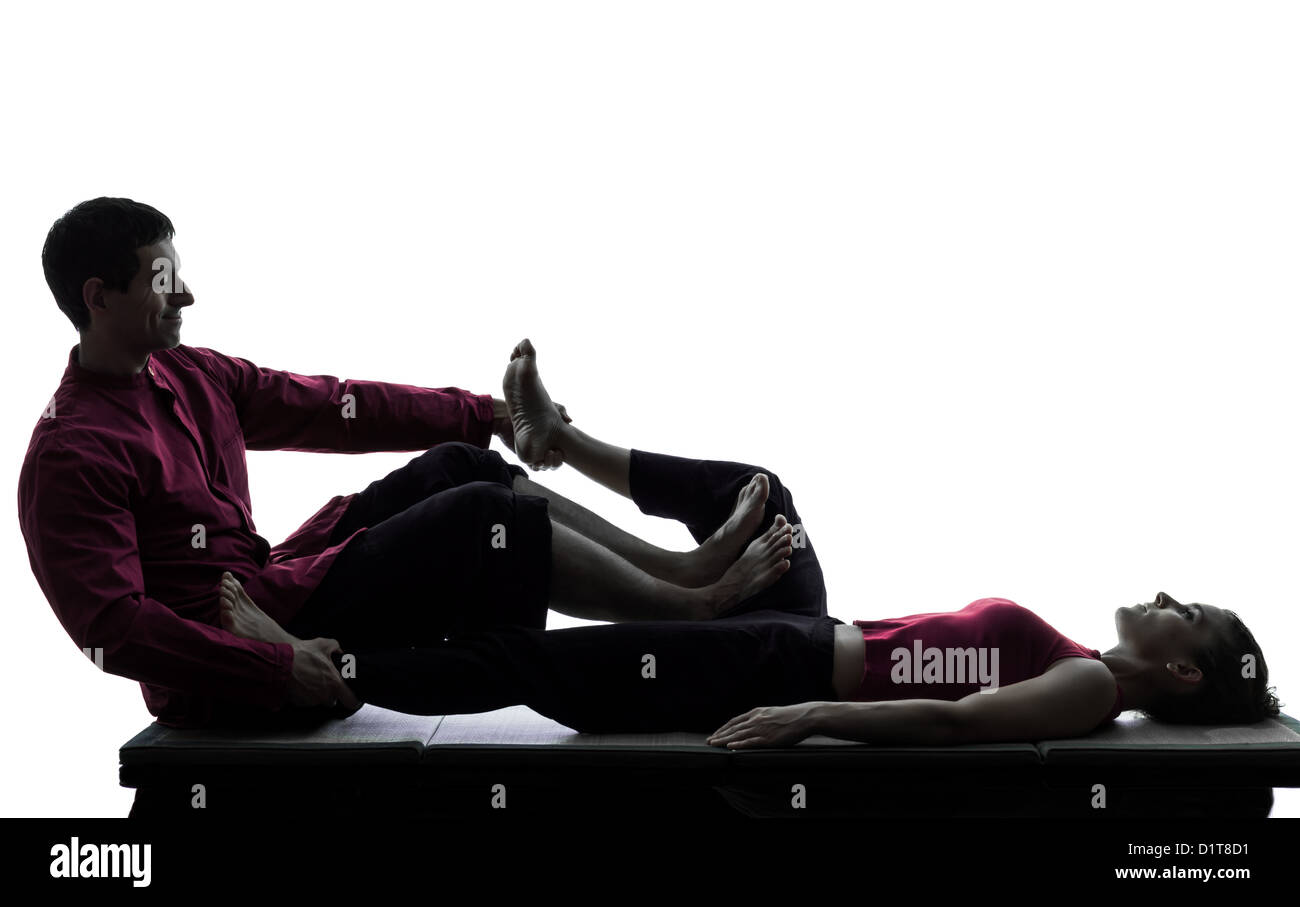 one man and woman performing feet legs thai massage in silhouette ...