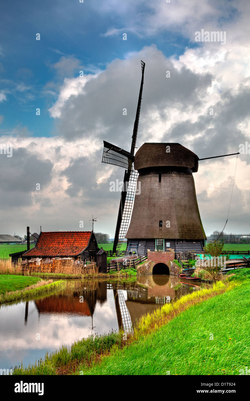 Image of a traditional Dutch windmill near a canal in a cloudy day ...