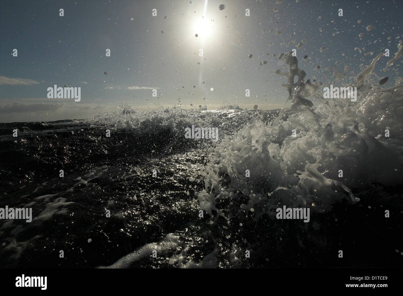 Waves crash over a reef in the early morning, backlit by the sun Stock ...