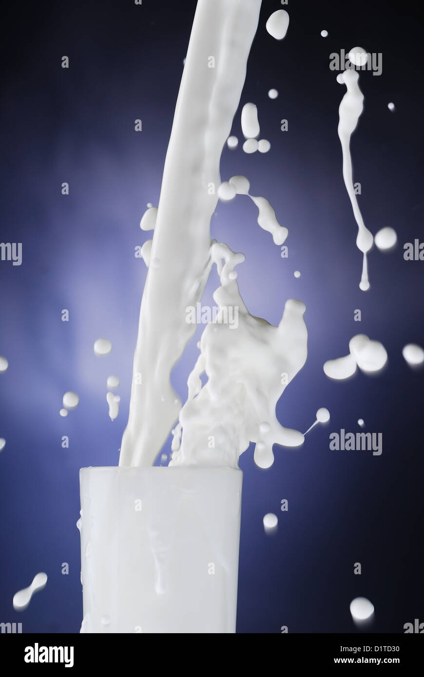 Milk splashing while being poured in a glass Stock Photo - Alamy