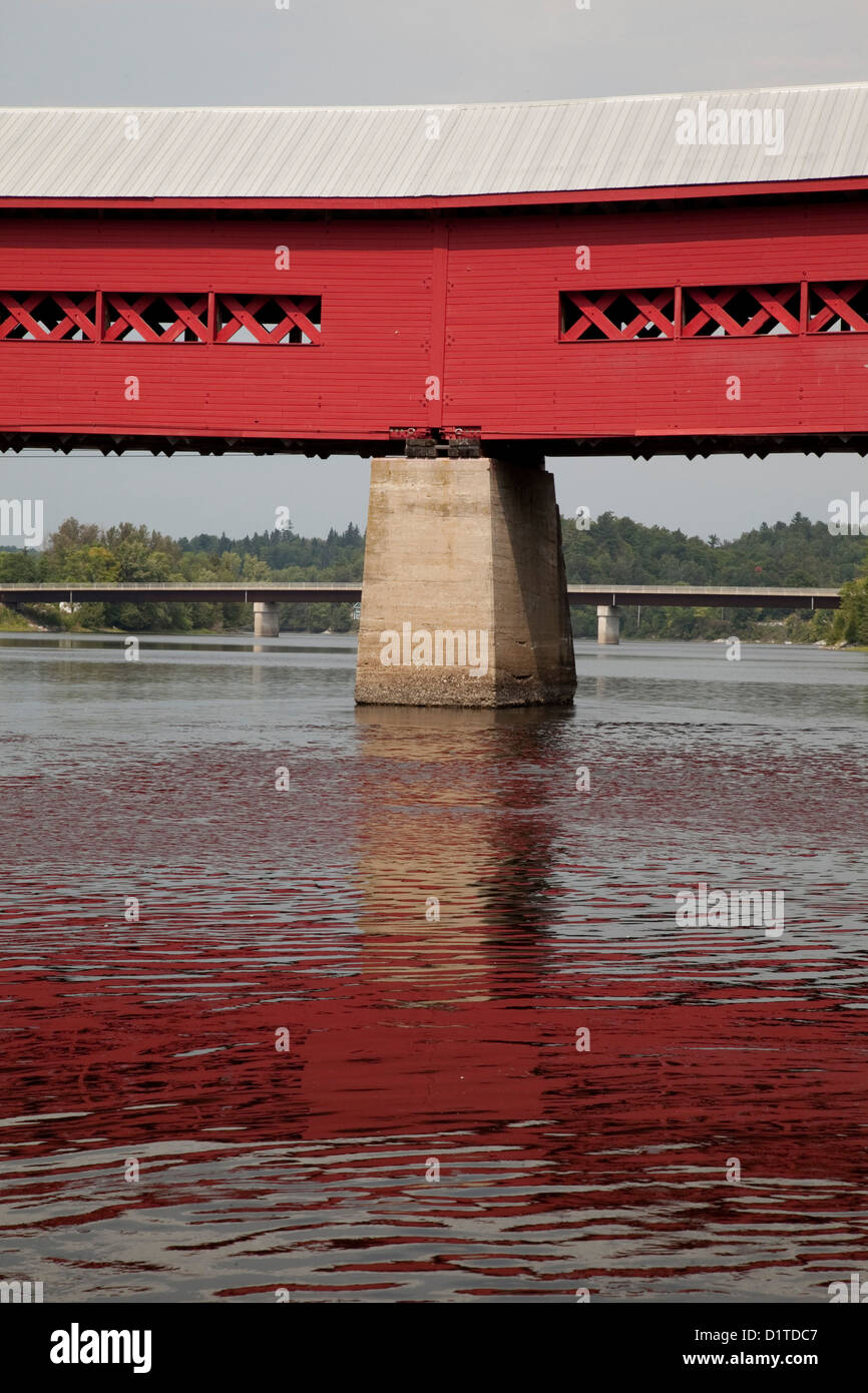 A vertical image of a red wooden foot bridge over the Ottawa River, the ...