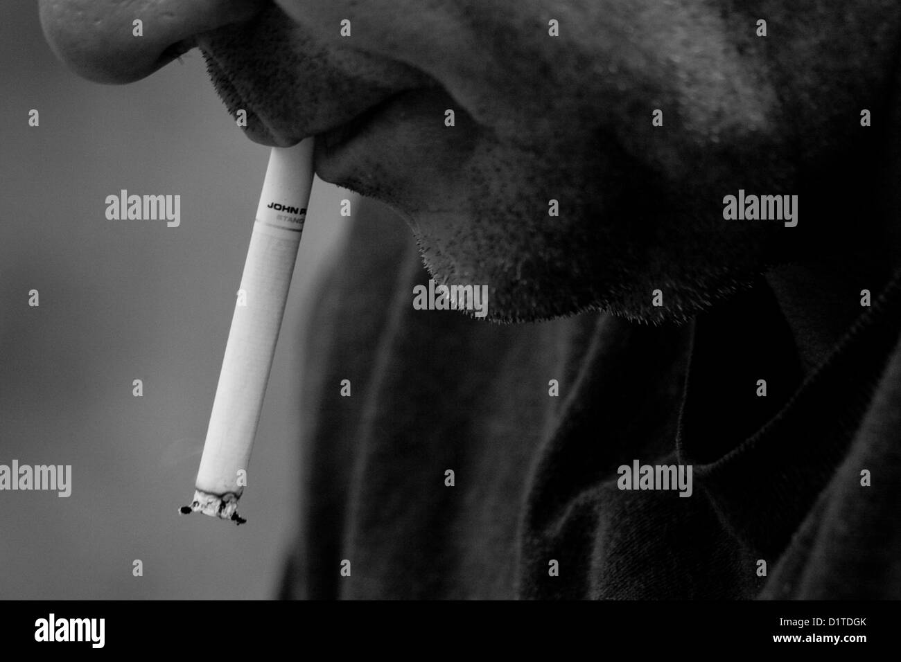A black and white portrait of a man's nose and mouth as he smokes a ...