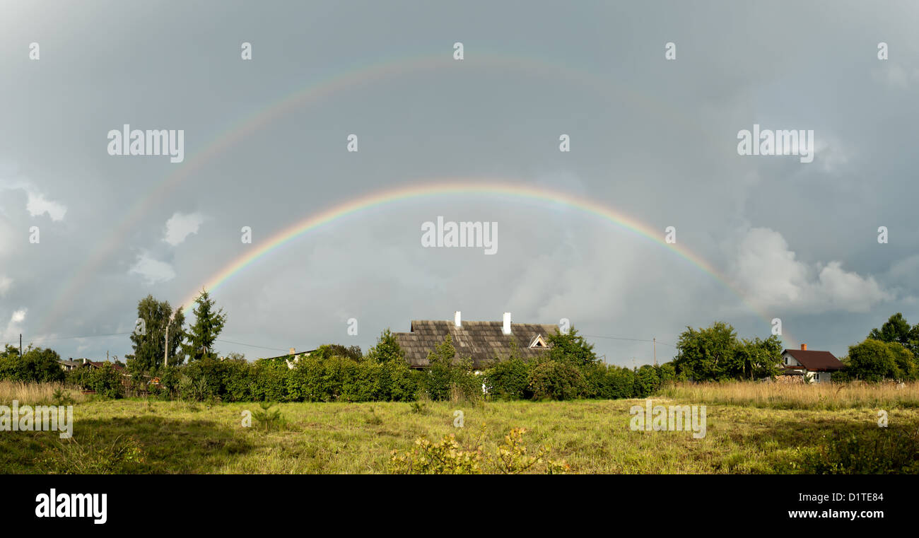 Rainbow over the village. Rural landscape with the real rainbow Stock ...