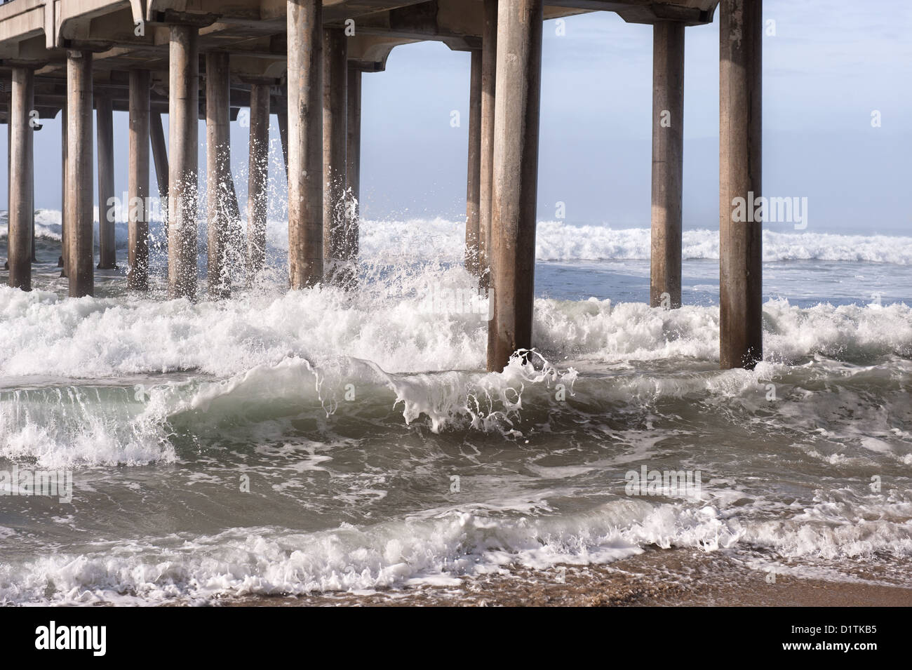 A rough day at the beach shows confused water movement around a pier ...