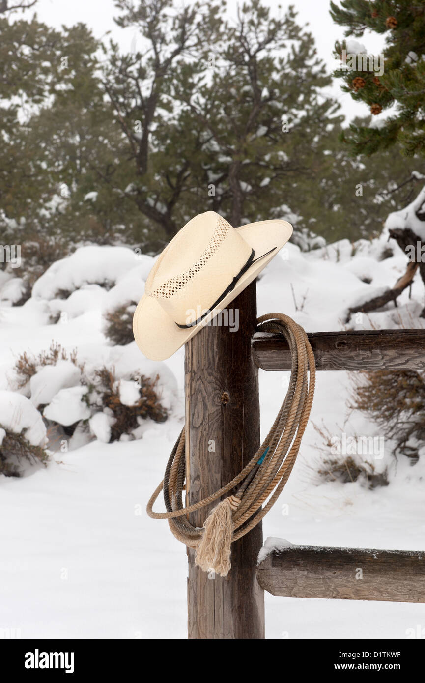 A cowboy's wrangler hat and lasso hanging on a corral fence post in a ...