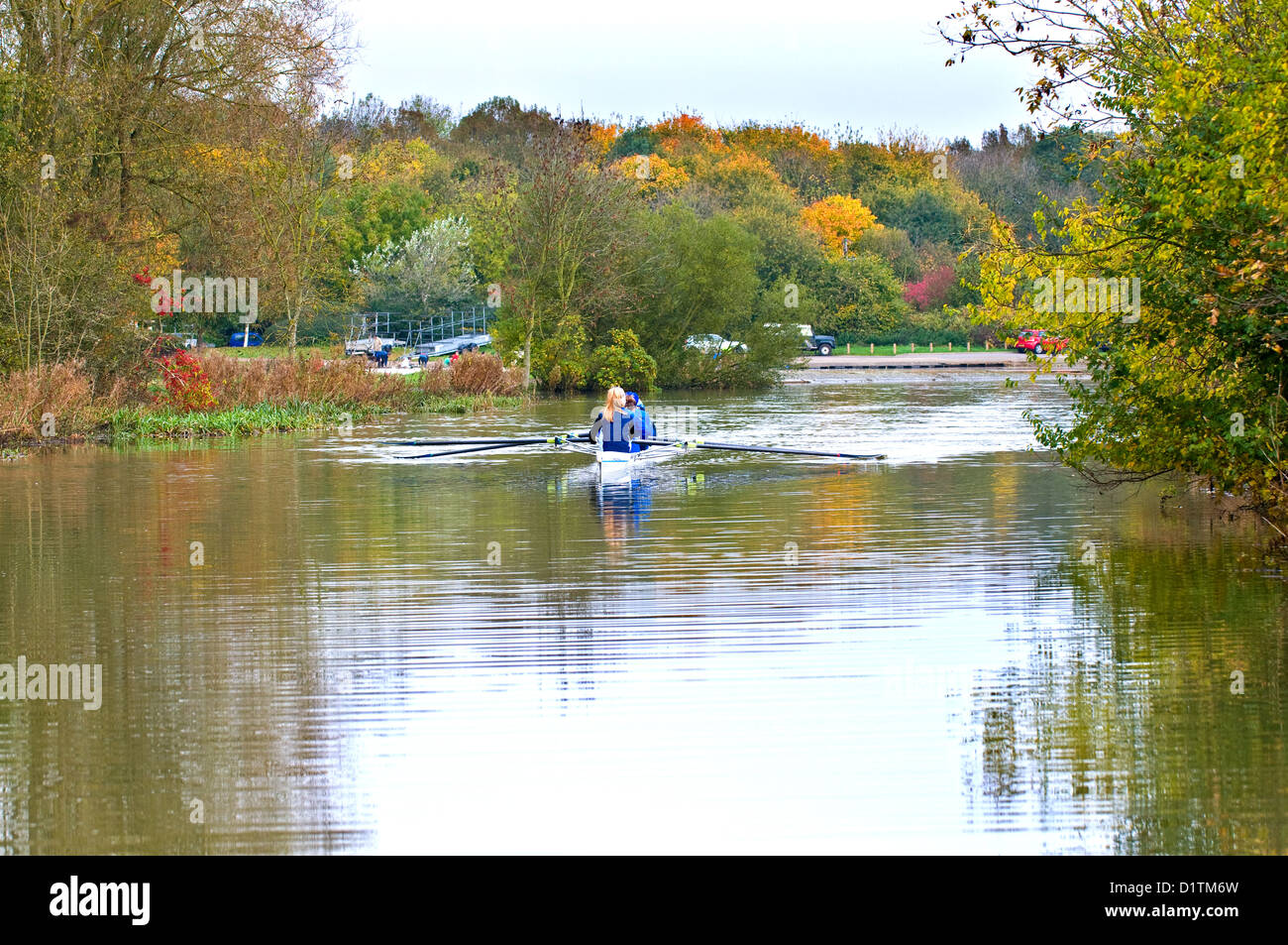 A rowing coxed four (4+) on the river Nene with Autumn covered trees in ...
