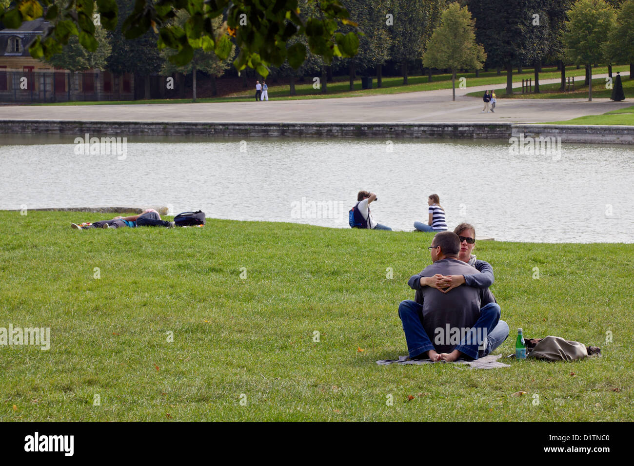 A young couple sit and hug each other in the gardens of the Palace of ...