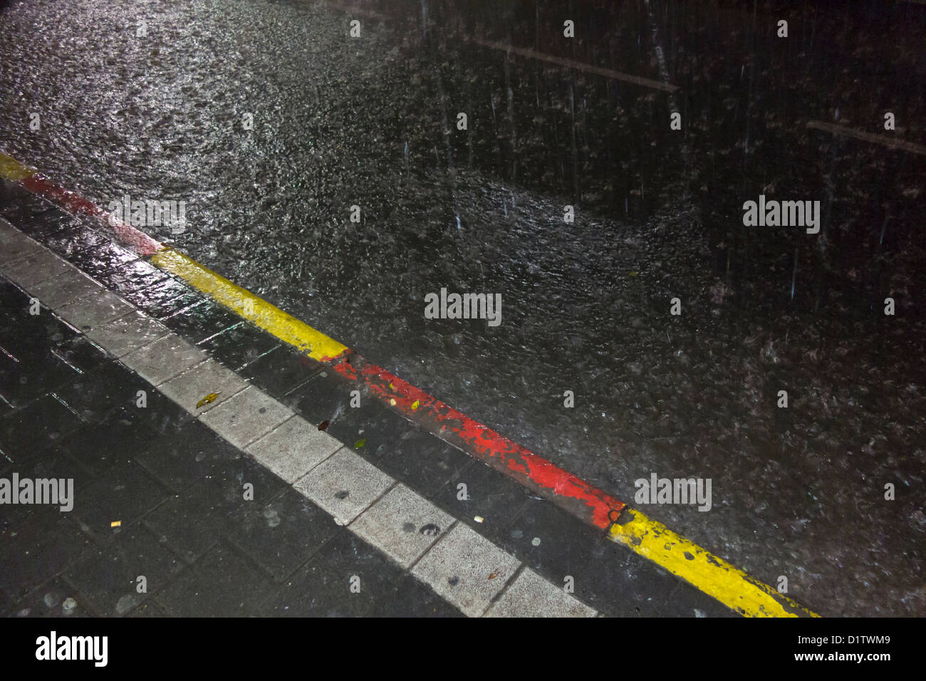 Rain falling on a pavement with sidewalk marking in winter in Tel Aviv ...