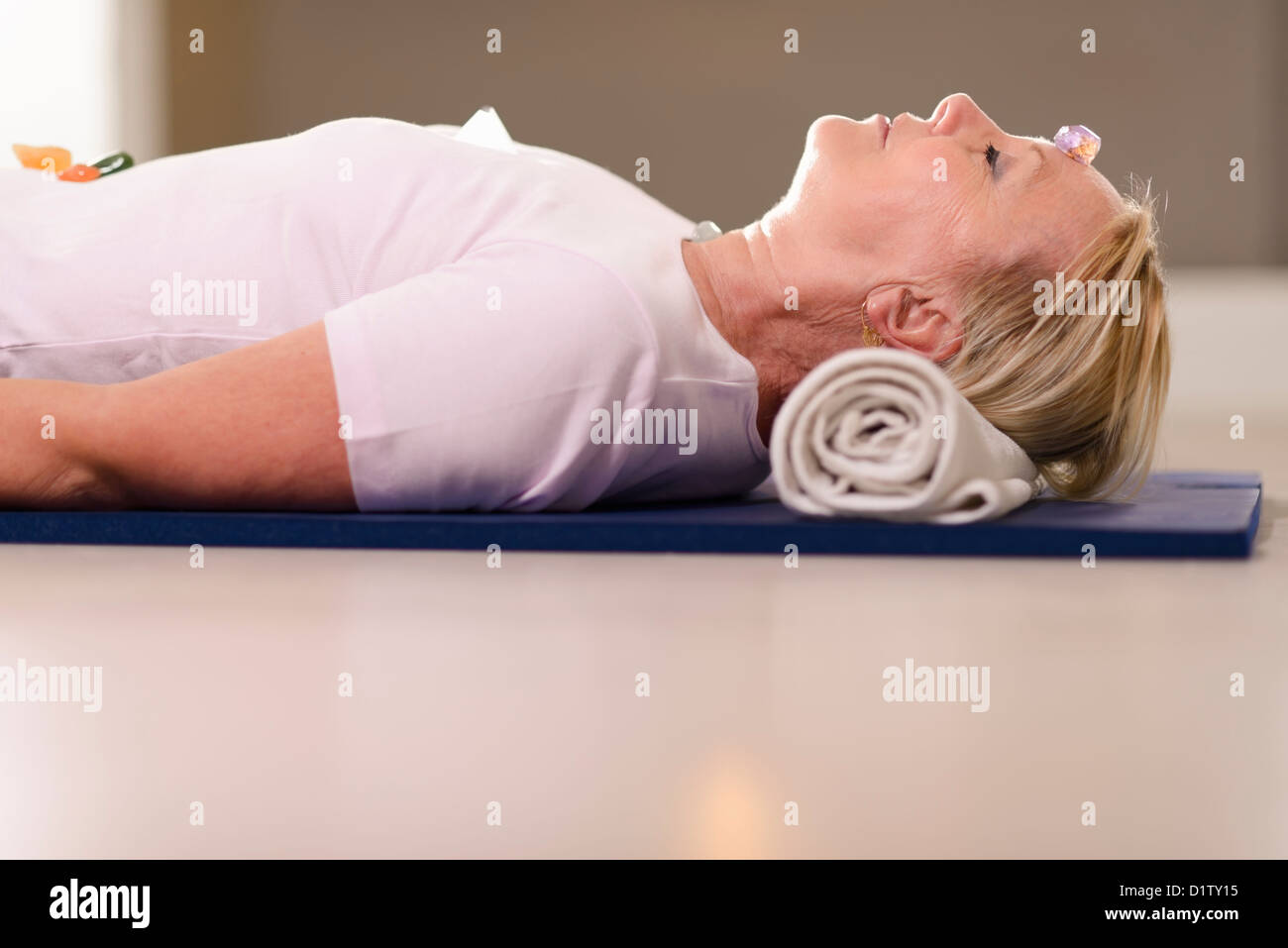 Senior woman relaxing and lying on pad with amethyst, quartz and other ...