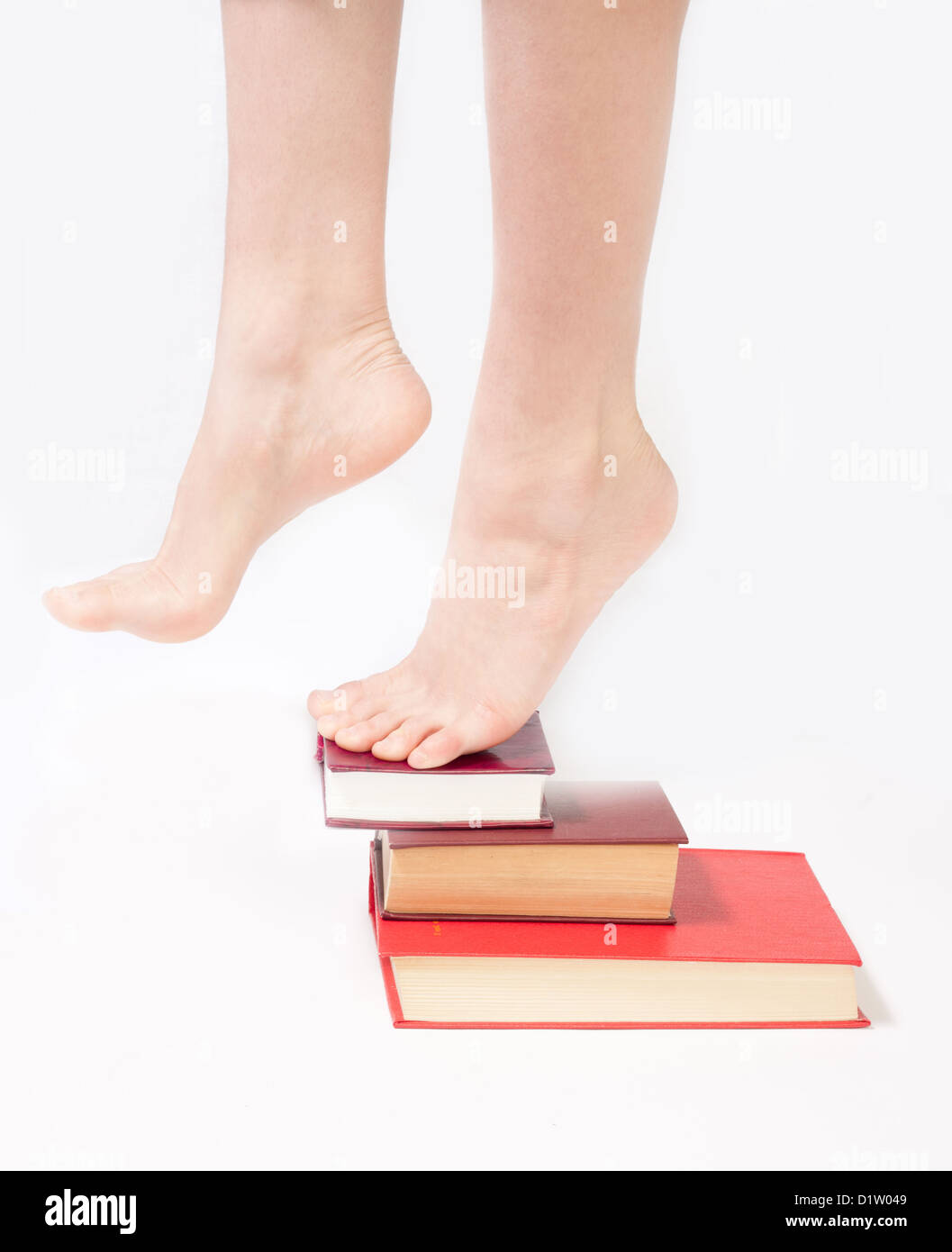 Person standing on a stack of books Stock Photo - Alamy