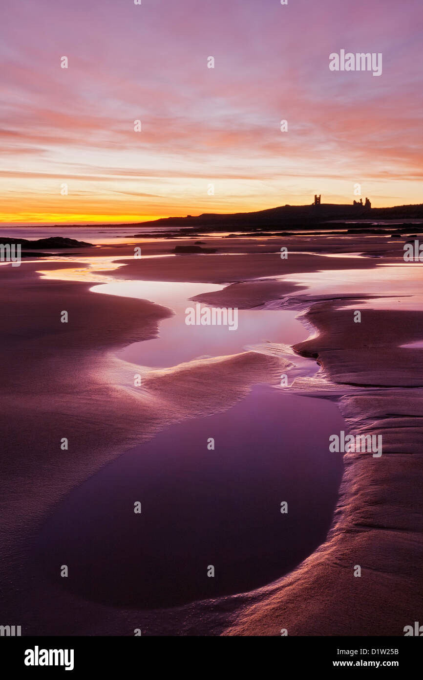 View along Embleton Bay at sunrise with silhouette of Dunstanburgh ...