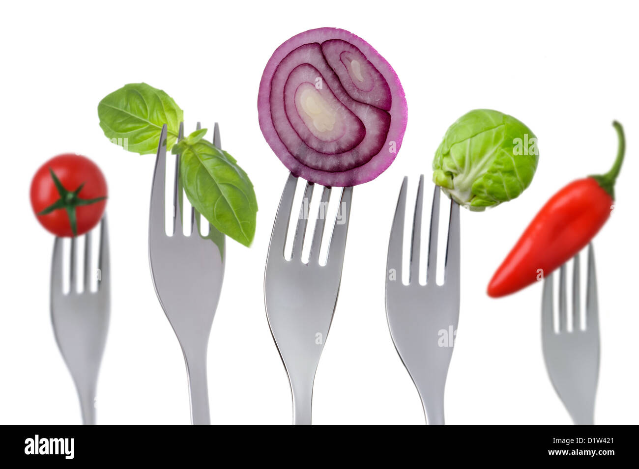 five different fruits and vegetables on forks isolated on a white ...