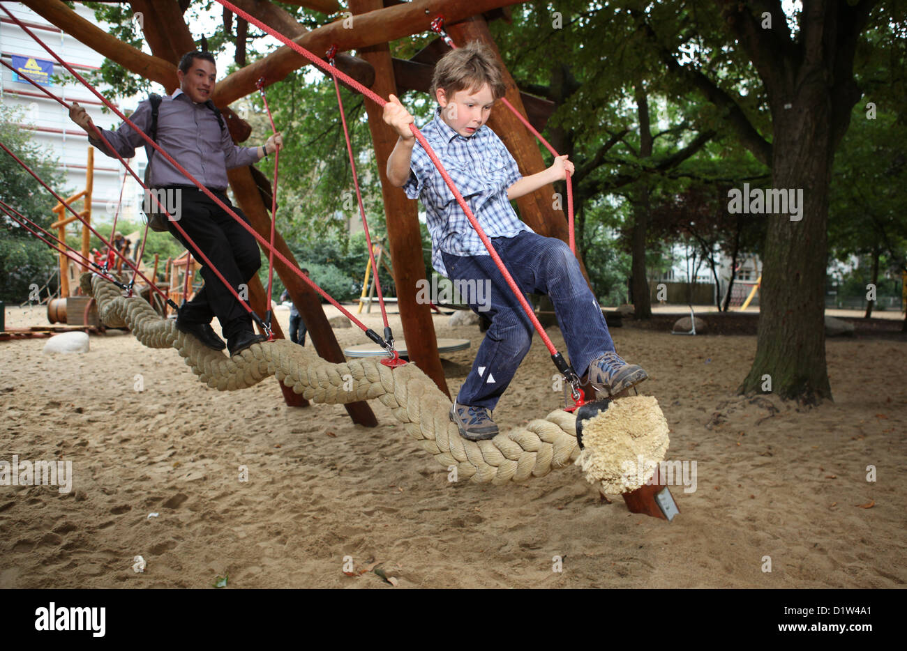 Berlin, Germany, a child and adolescent walk on a rope behind the other ...