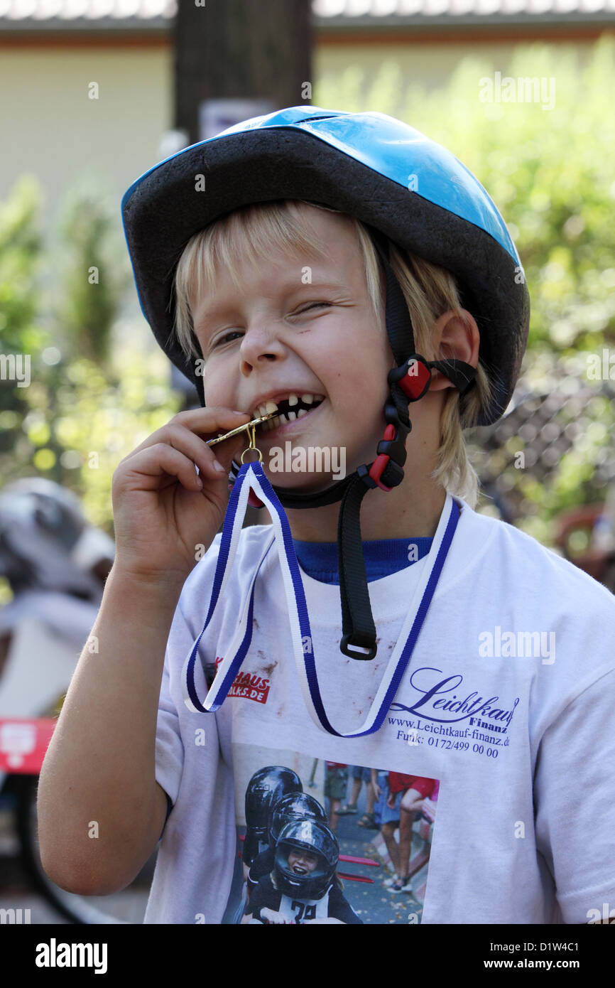 Neuenhagen, Germany, Boy biting a gold medal Stock Photo - Alamy