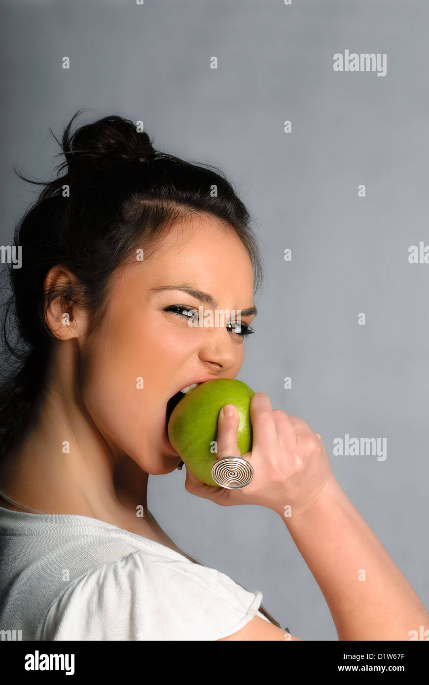 Beautiful young woman biting an apple portrait isolated Stock Photo - Alamy