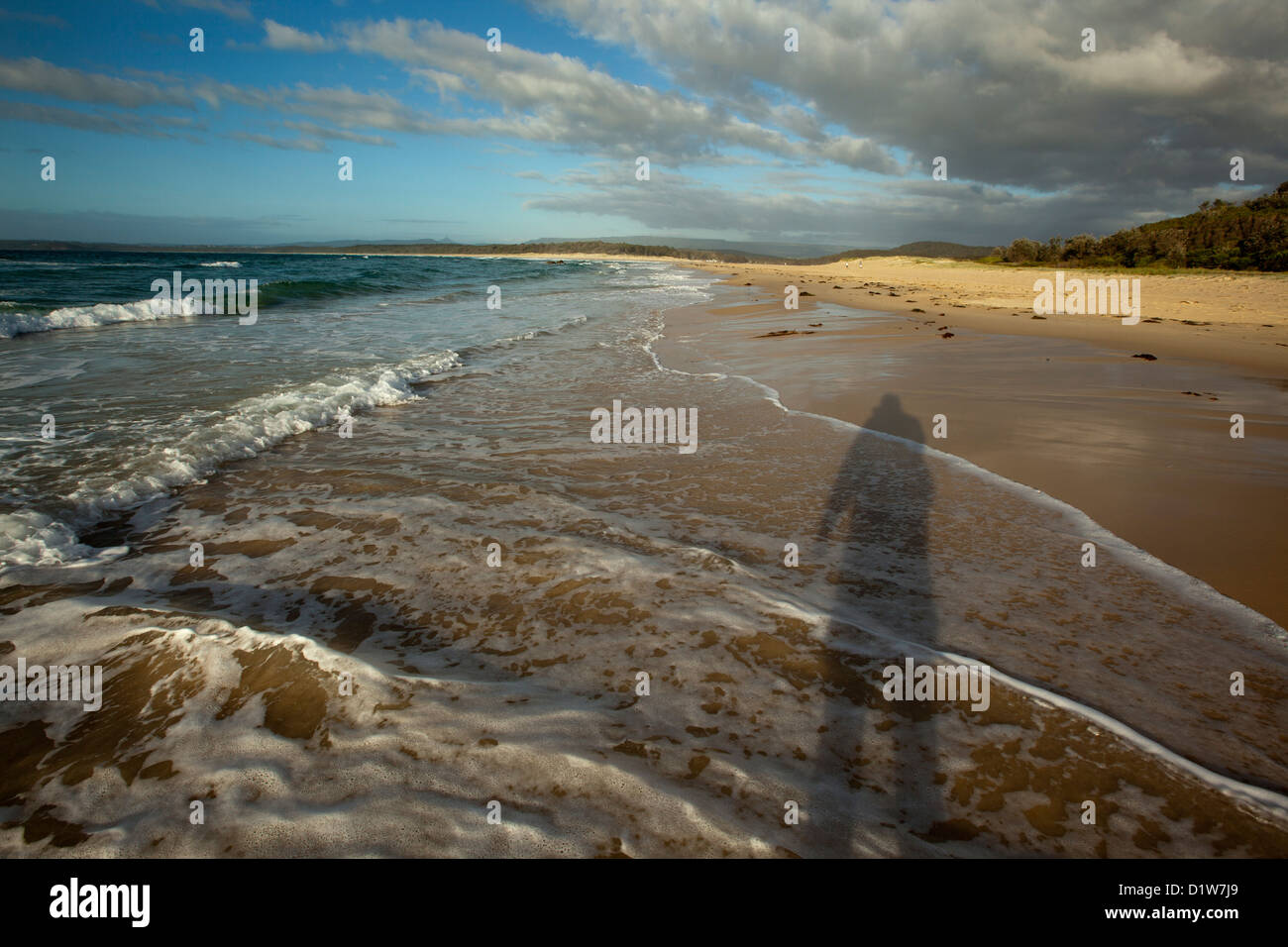Beach walker's shadow at sunrise on Manyana Beach, near Lake Conjola ...
