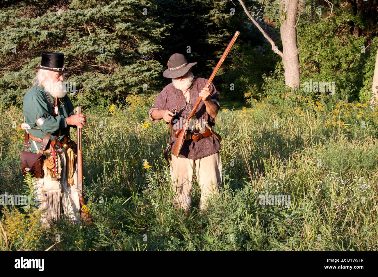 Two mountain men hunting with one trapper filing his rifle with gun ...