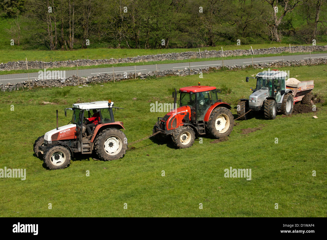 Tractors linked together pulling out a tractor and limespreader stuck ...