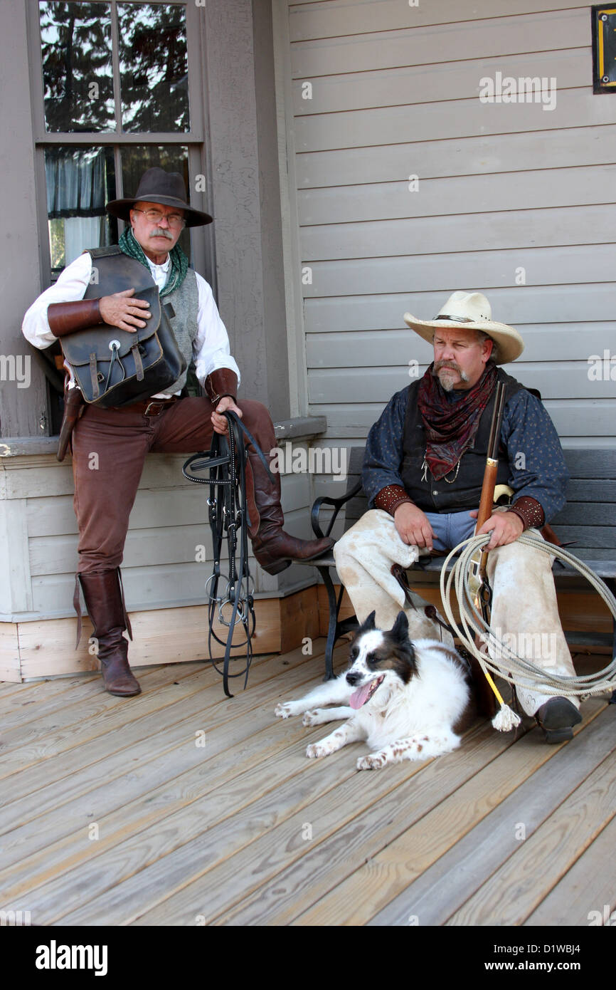 Two cowboys sitting on the train depot platform Stock Photo - Alamy