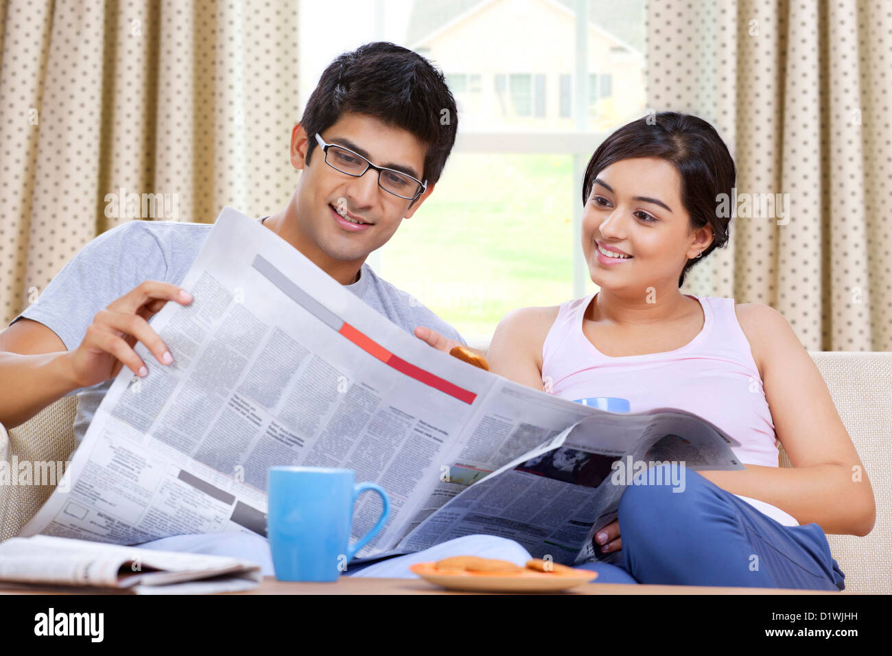 Young couple reading newspaper together Stock Photo - Alamy