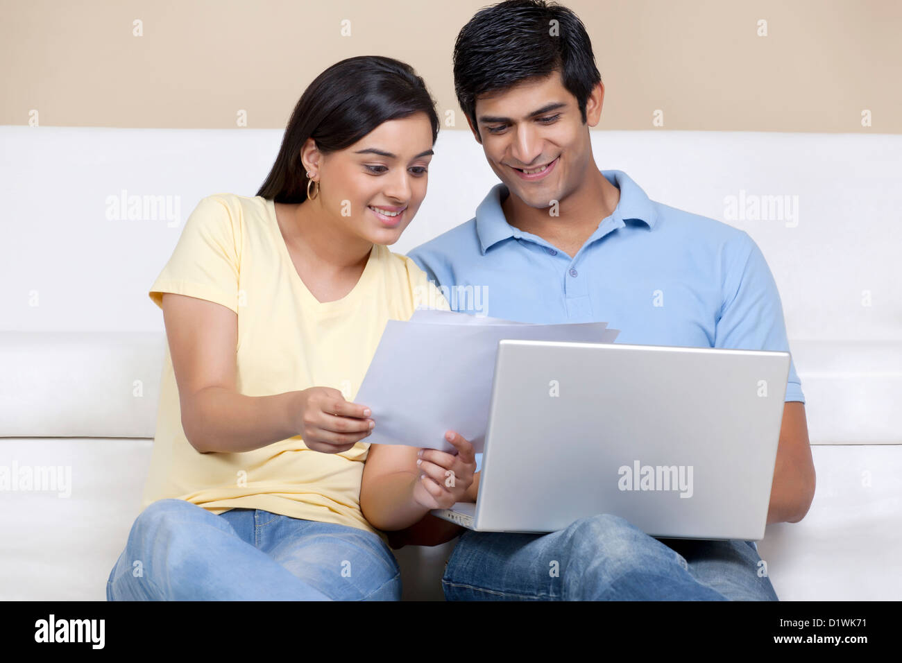 Young Indian couple reading document while using laptop Stock Photo - Alamy
