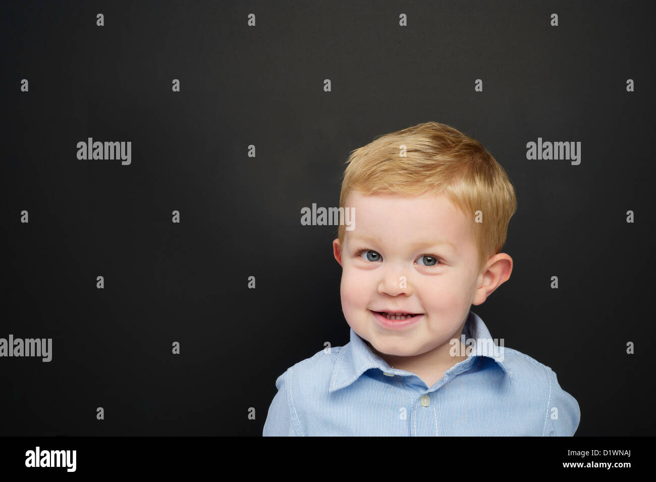 Smart young boy wearing a blue striped shirt standing in front of a ...