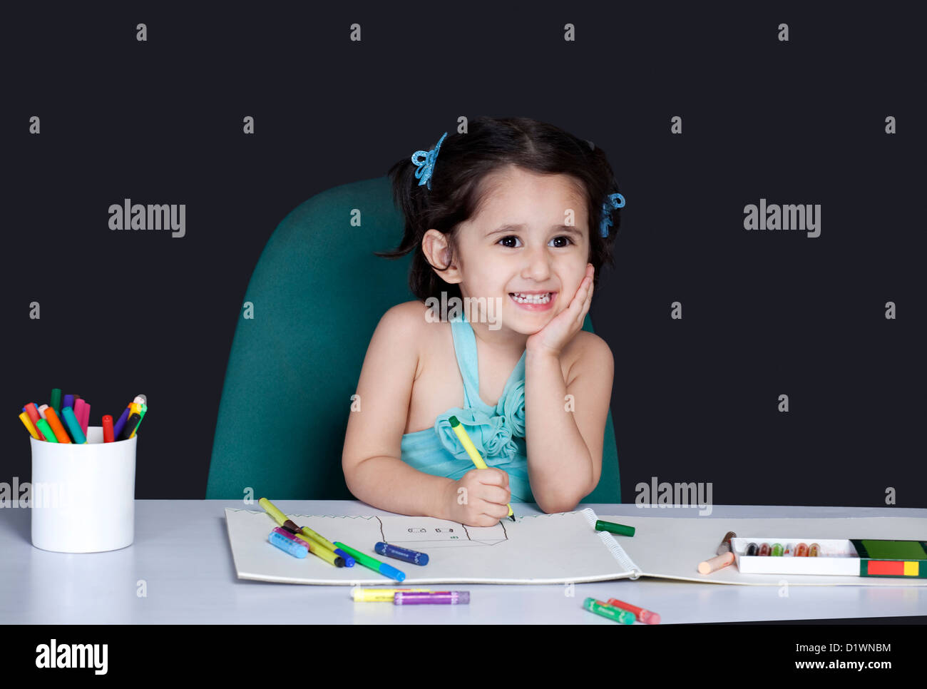 Cute little girl smiling while drawing Stock Photo - Alamy