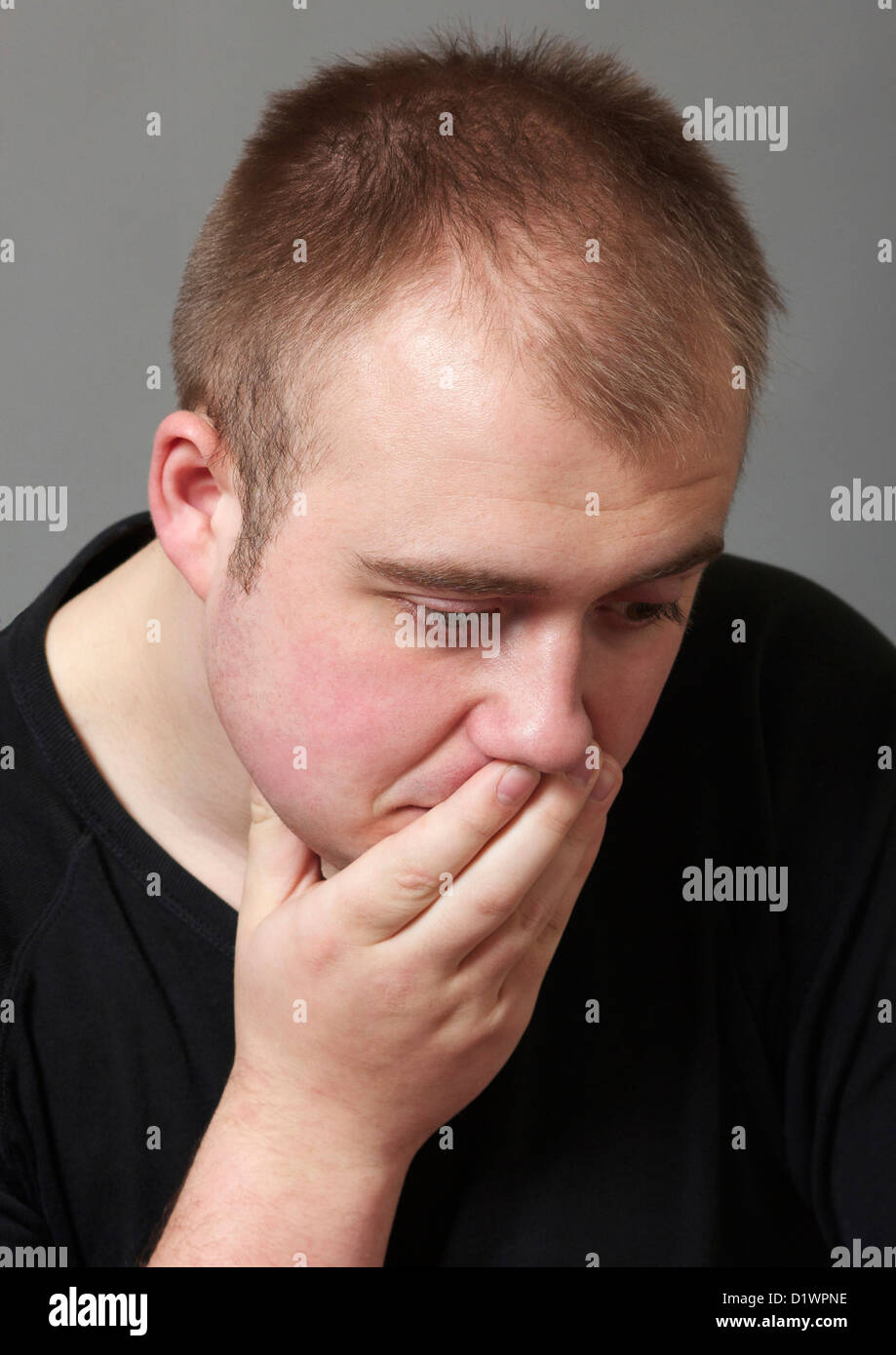 Young Man with hand over his mouth, deep in thought Stock Photo - Alamy