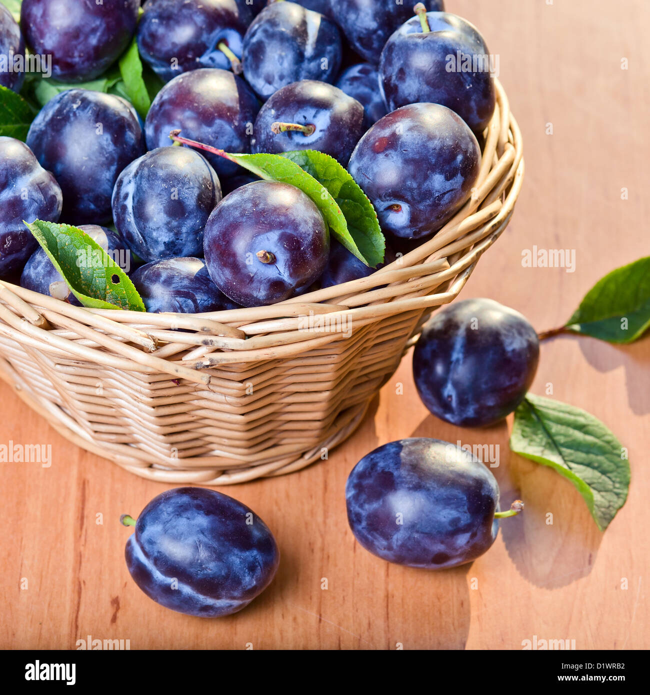 ripe plums in basket on a wood table Stock Photo - Alamy