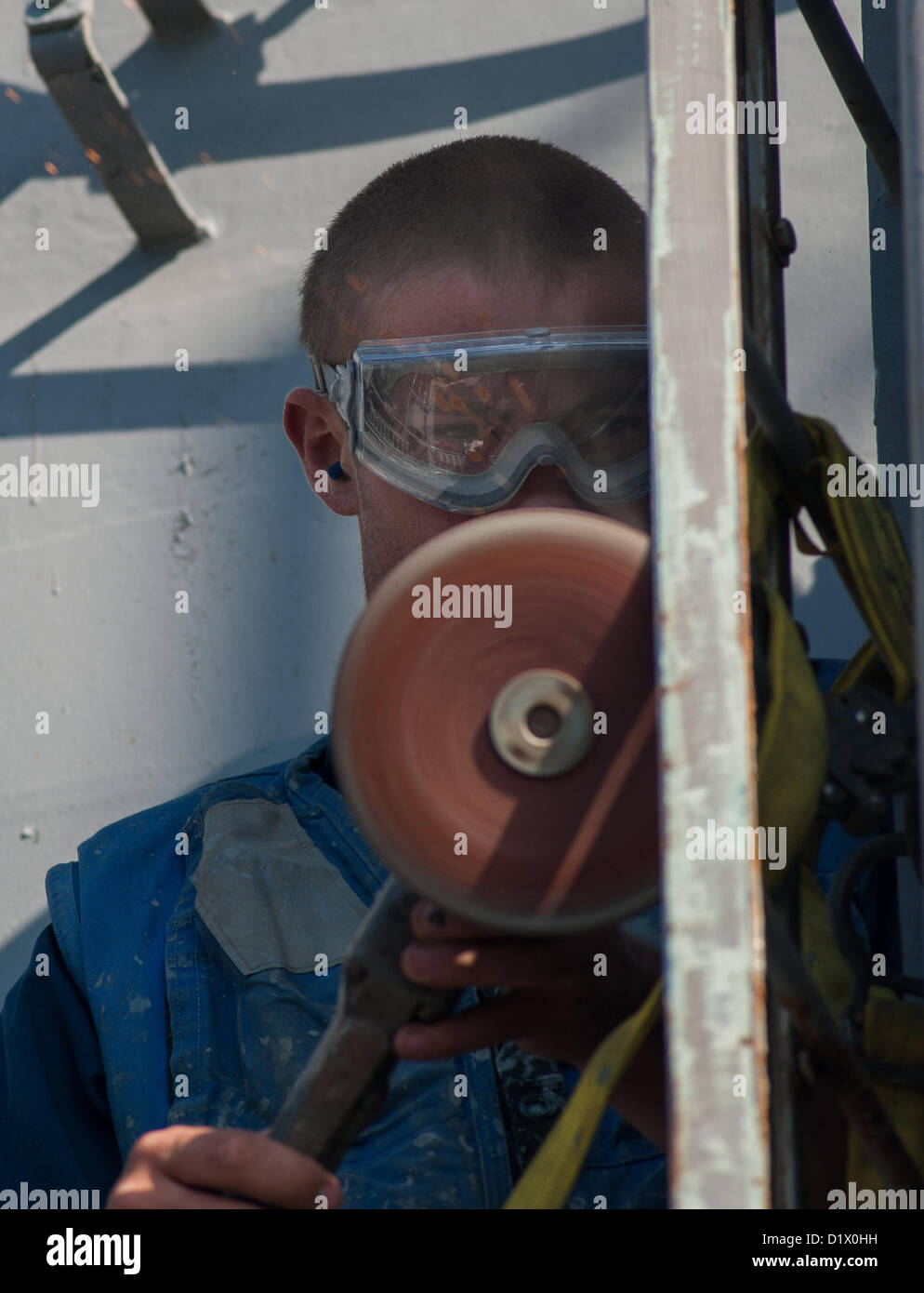 Boatswain's Mate 3rd Class Jacob Birch sands rust off a sliding pad-eye ...