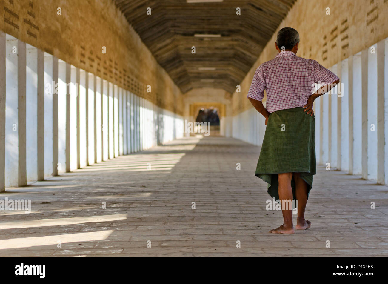 Man standing in traditional dress at entrance to Schwezigon Paya, Bagan ...