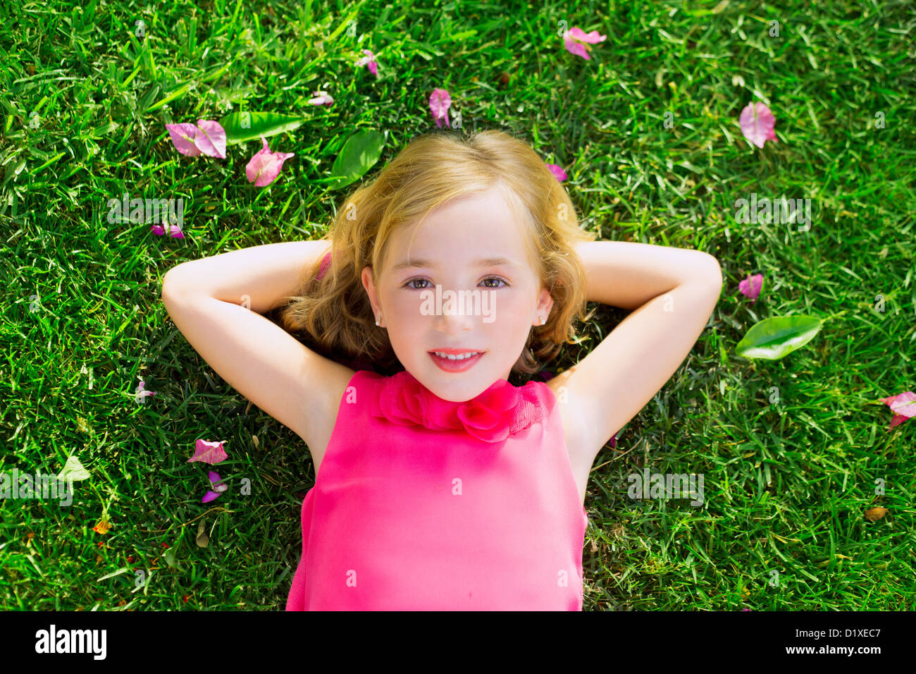 Blond Kid Girl Lying On Garden Grass Smiling Happy Aerial View Stock