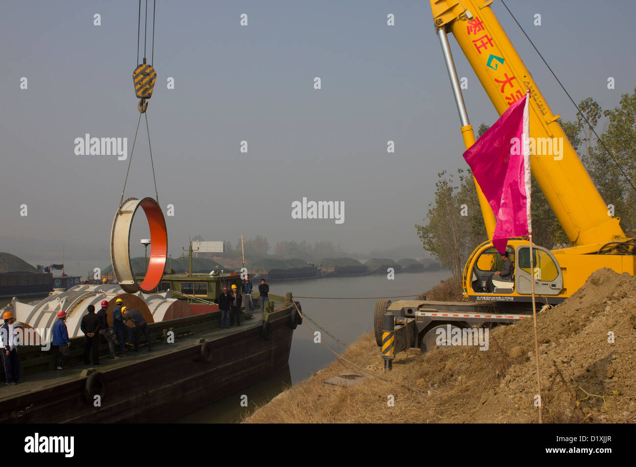 Crane lifting metal ring off a barge at Huinanzhuang pumping station ...