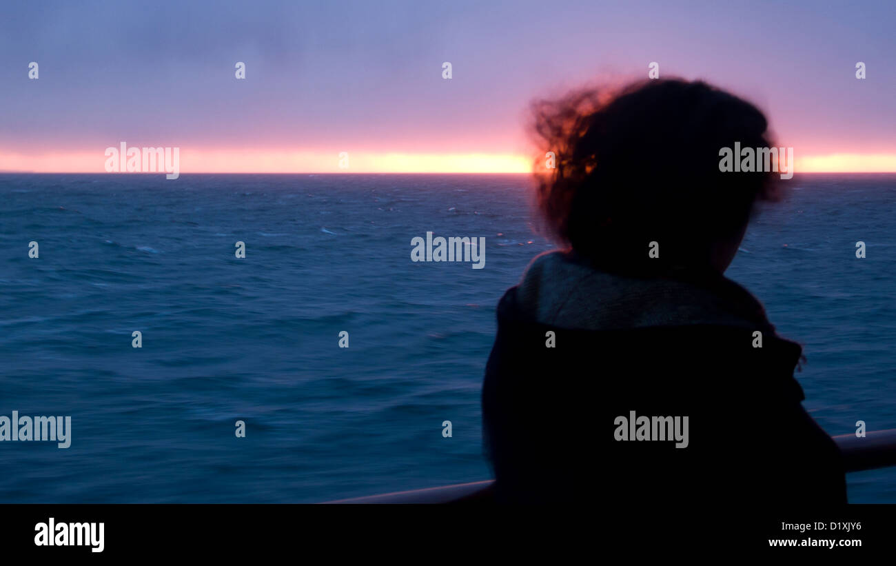 Figure on ferry in silhouette against sunset, open sea Stock Photo - Alamy