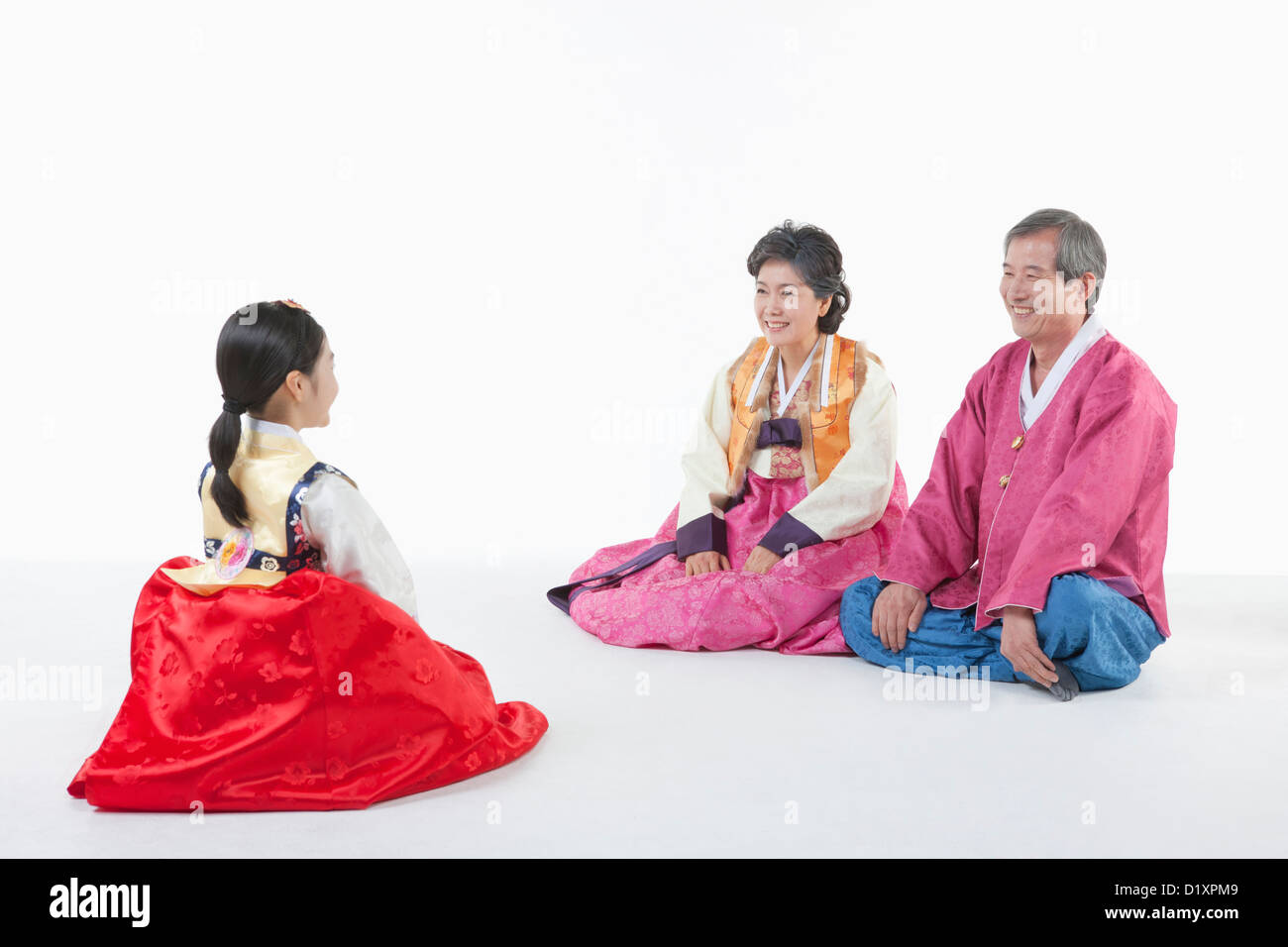 a girl sitting in front of parents wearing Hanbok Stock Photo - Alamy