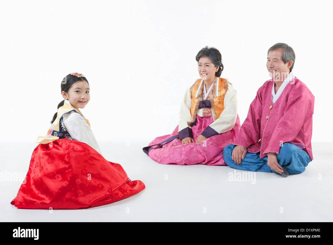 a girl sitting in front of parents wearing Hanbok Stock Photo - Alamy