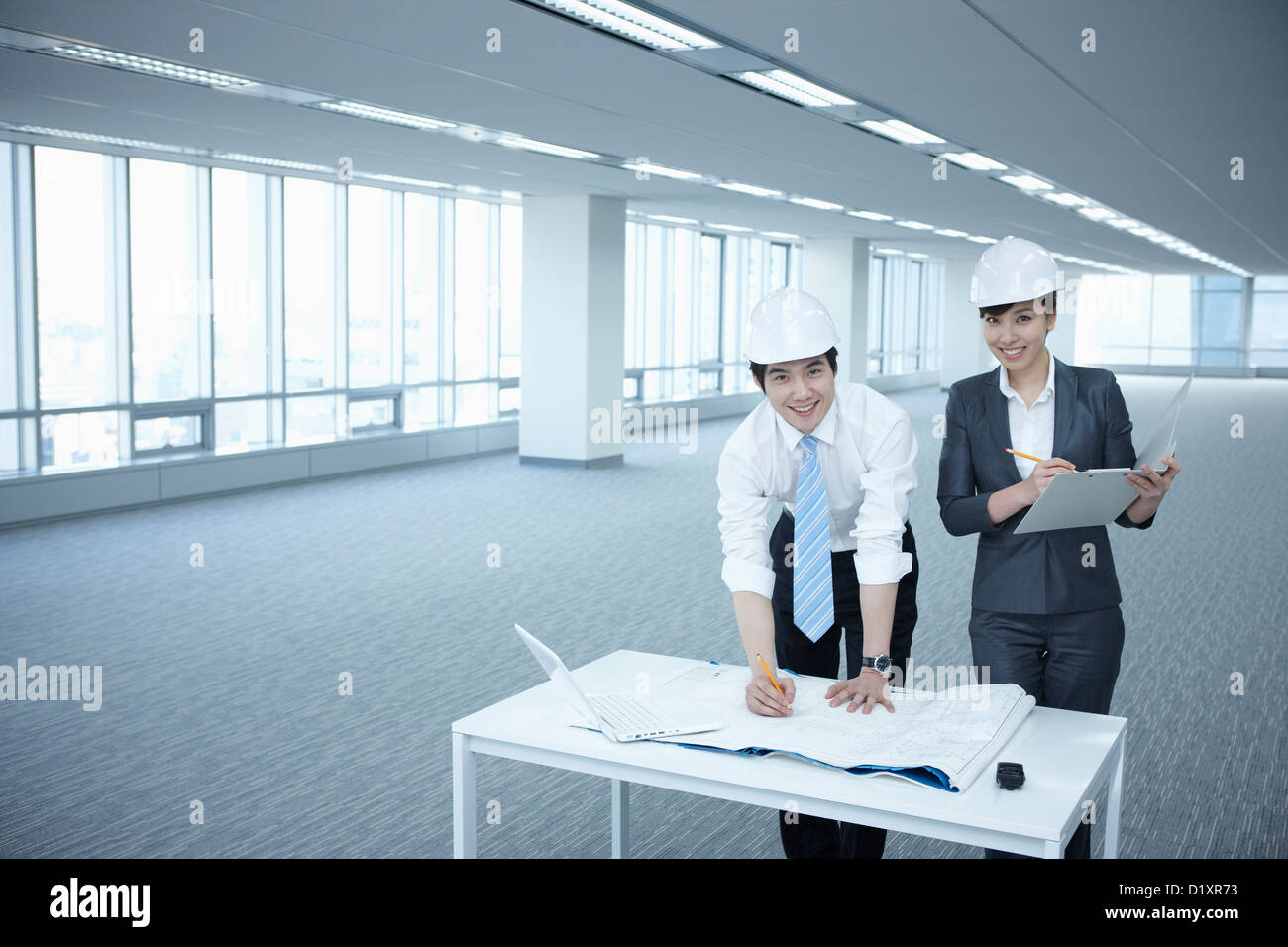 architect executives posing at camera with blueprints on a desk of an ...