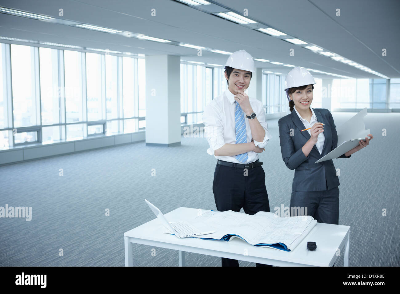 architect executives posing at camera with blueprints on a desk of an ...