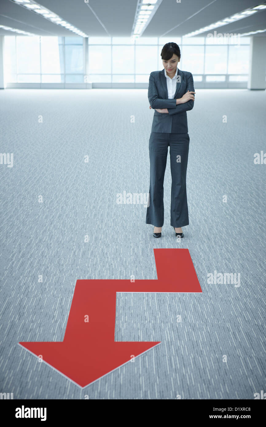 a businesswoman standing in front of an arrow in an empty room Stock ...