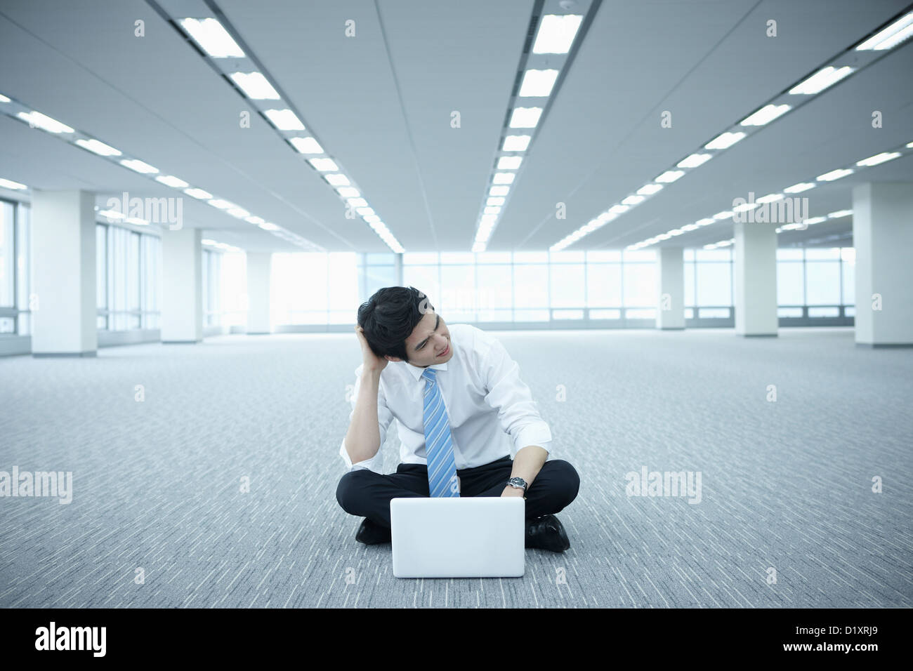 a stressed businessman using laptop on the floor of an empty room Stock ...