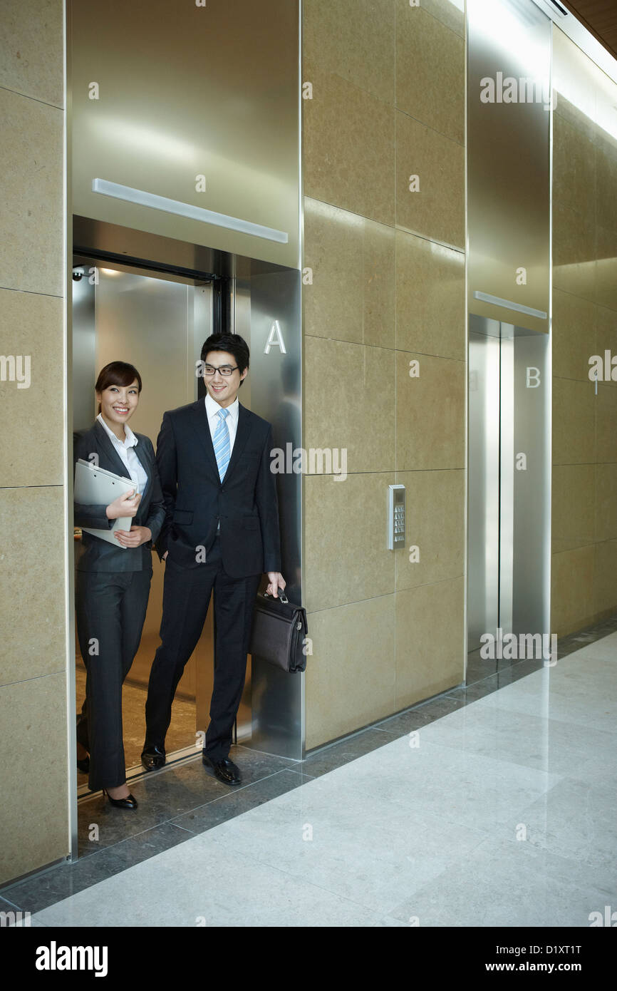a businessman and woman getting of an elevator Stock Photo - Alamy