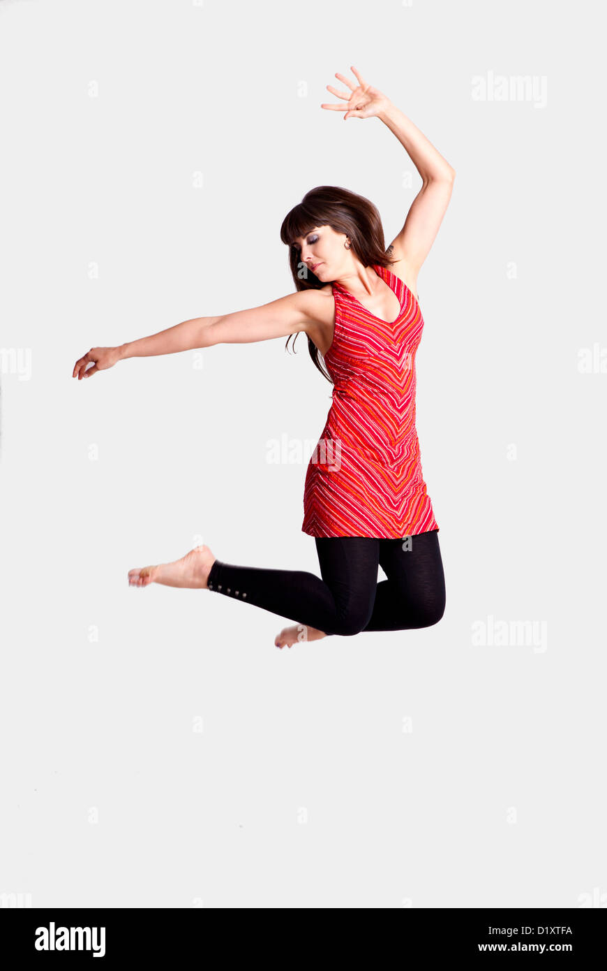 Beautiful happy woman jumping over a grey background Stock Photo - Alamy