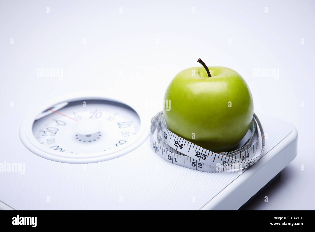 measurement tape surrounding apple on a weight scale Stock Photo - Alamy