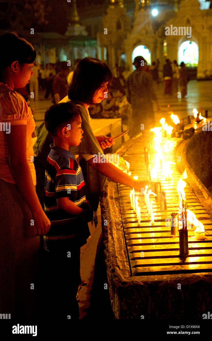 A young boy lighting a candle at the Shwedagon Paya located in (Rangoon ...